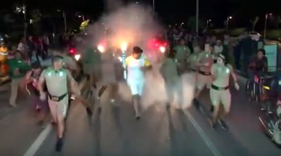 Man uses fire extinguisher to try and blow out the Olympic flame