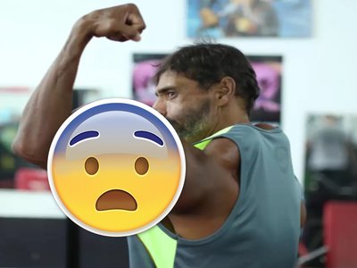 Bodybuilder pumps oil into his muscles